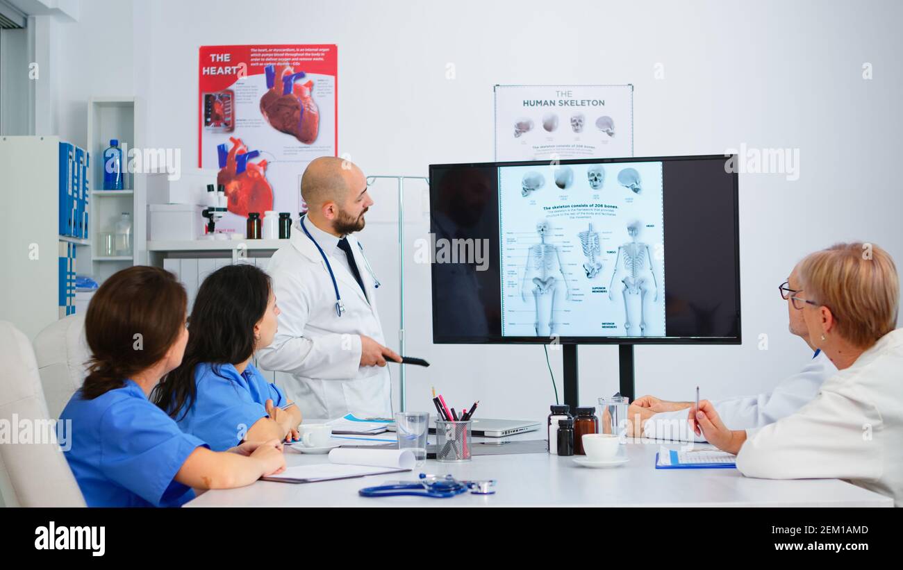 Experienced man doctor analysing human skeleton image together with ...