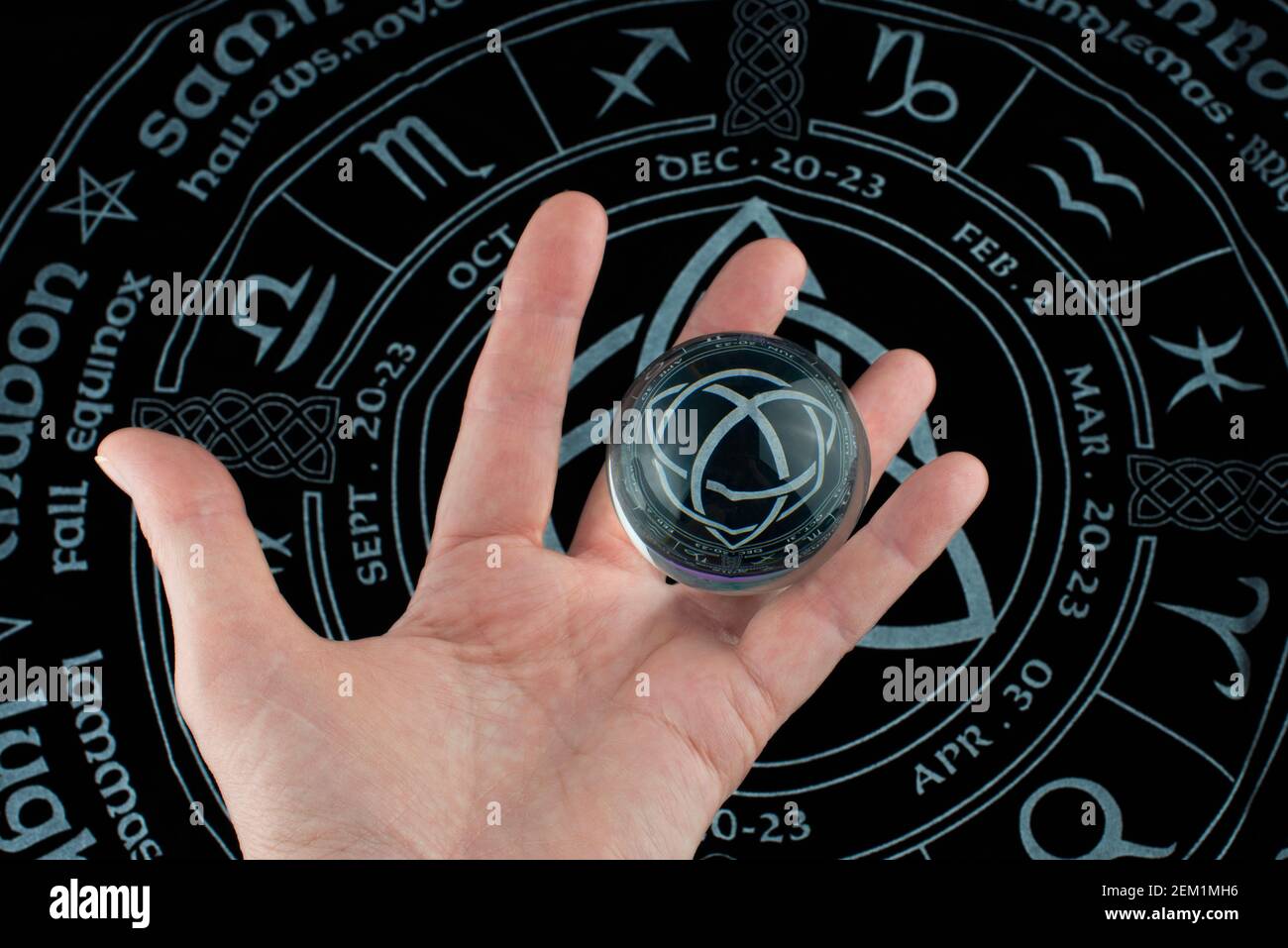 Hand holding a glass ball with horoscope reflections. Black background ...