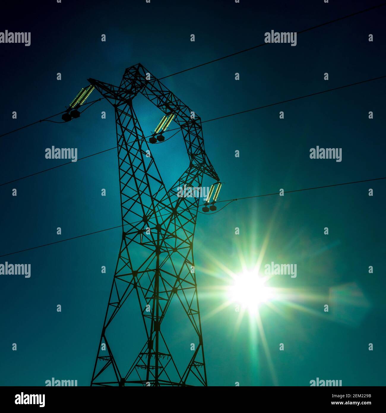 Power lines silhouetted against a bright sun on a clear day in an open ...