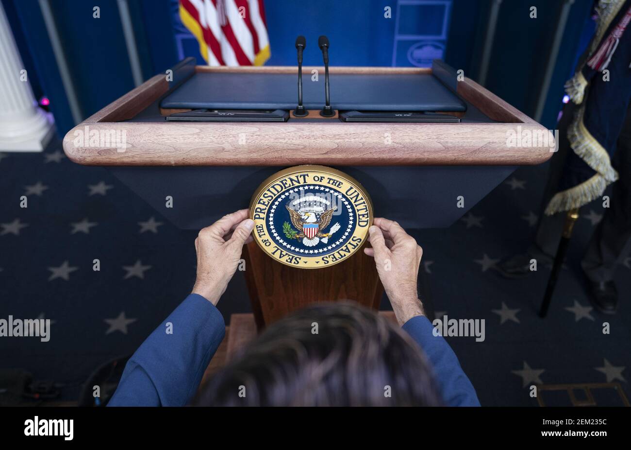 Communications staff installs the presidential seal on the lectern ...