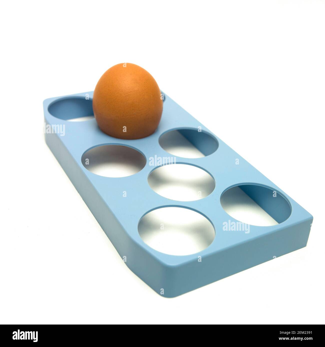 Bright egg placed in a blue egg mold with multiple circular cavities on ...