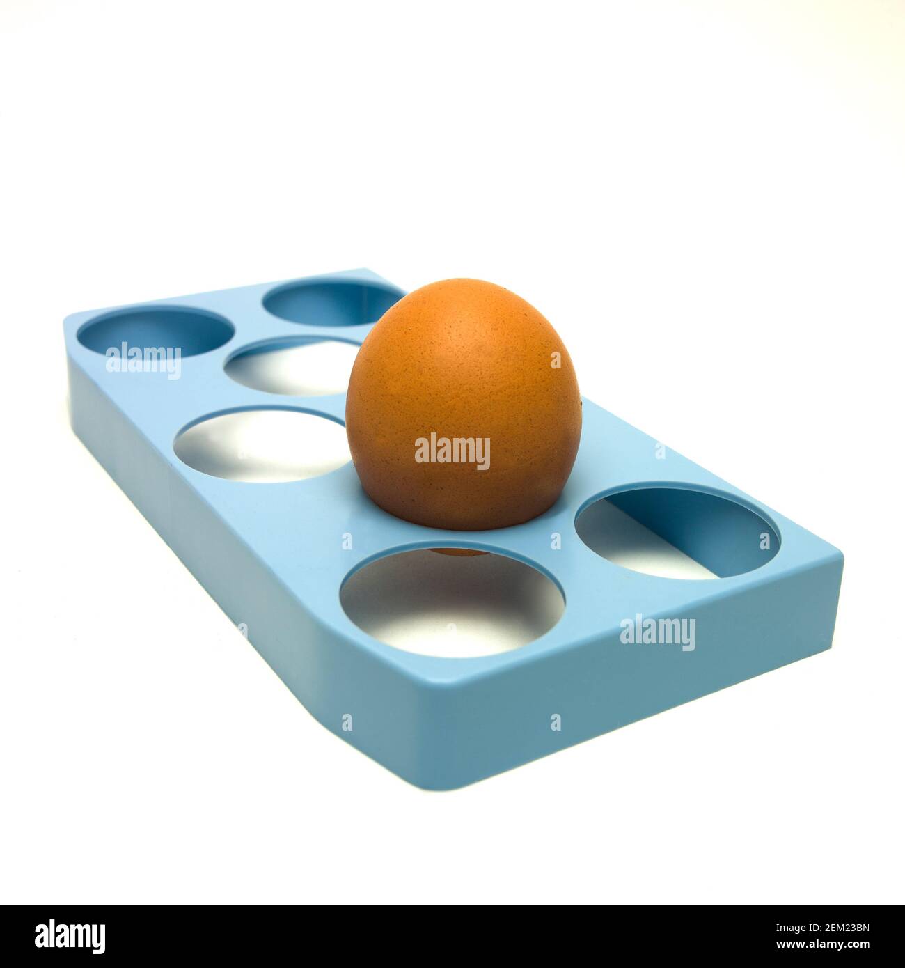 Bright egg placed in a blue egg mold with multiple circular cavities on ...