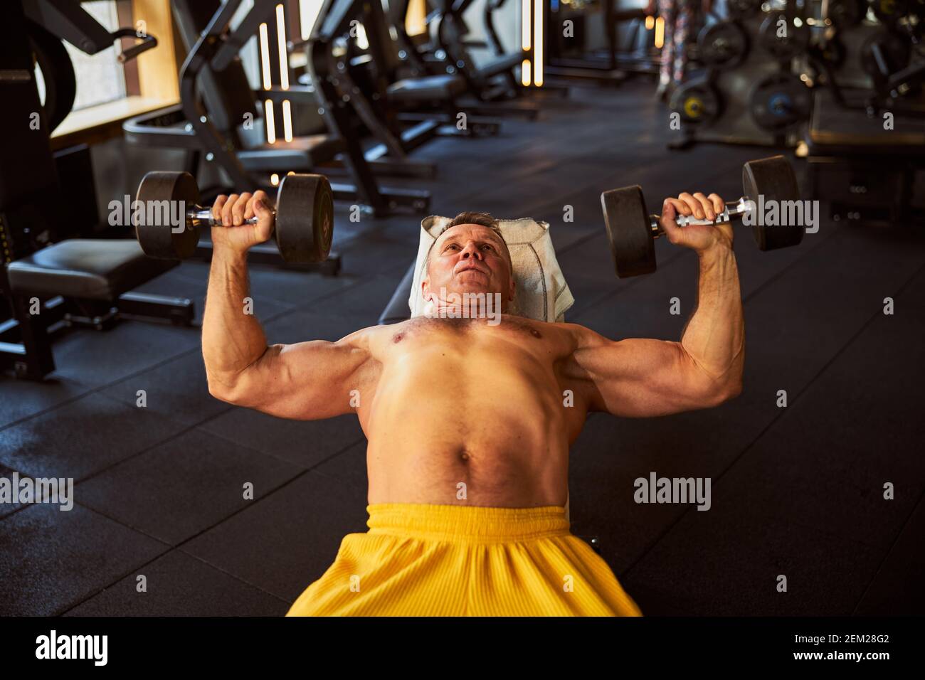 Committed muscular man doing exercises with dumbbells Stock Photo - Alamy