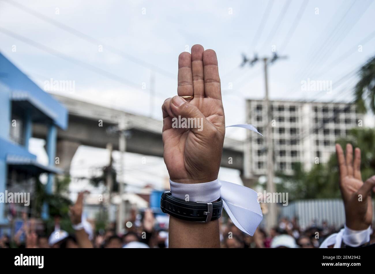 A protester with a white ribbon makes the three finger salute during a ...
