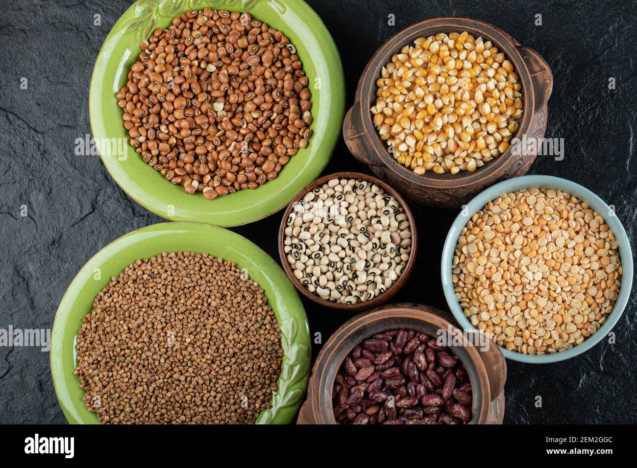 Different kinds of bean seeds, lentil, peas in dishes on a dark ...