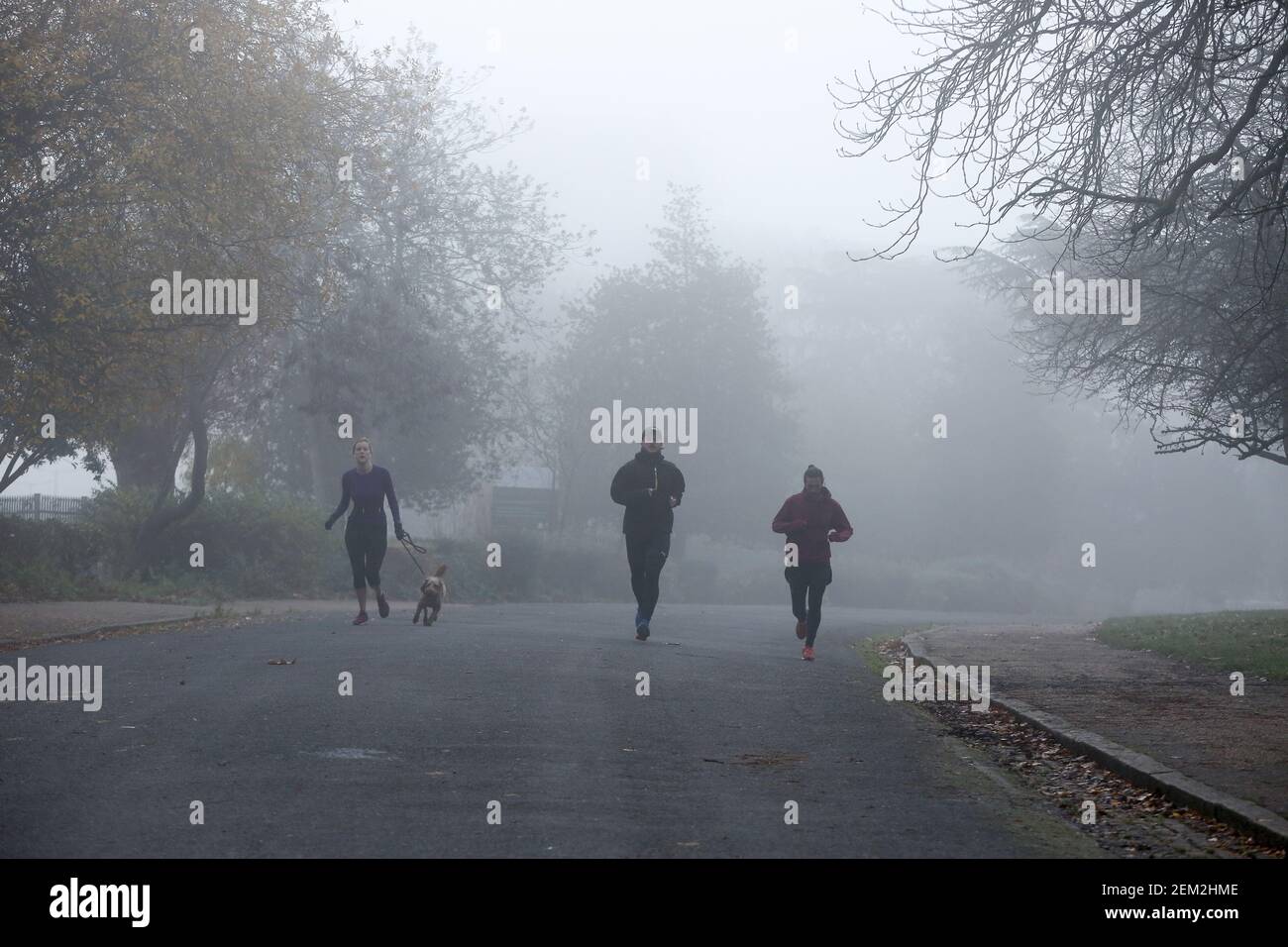 People jog amidst dense fog in London. Freezing cold and foggy weather ...