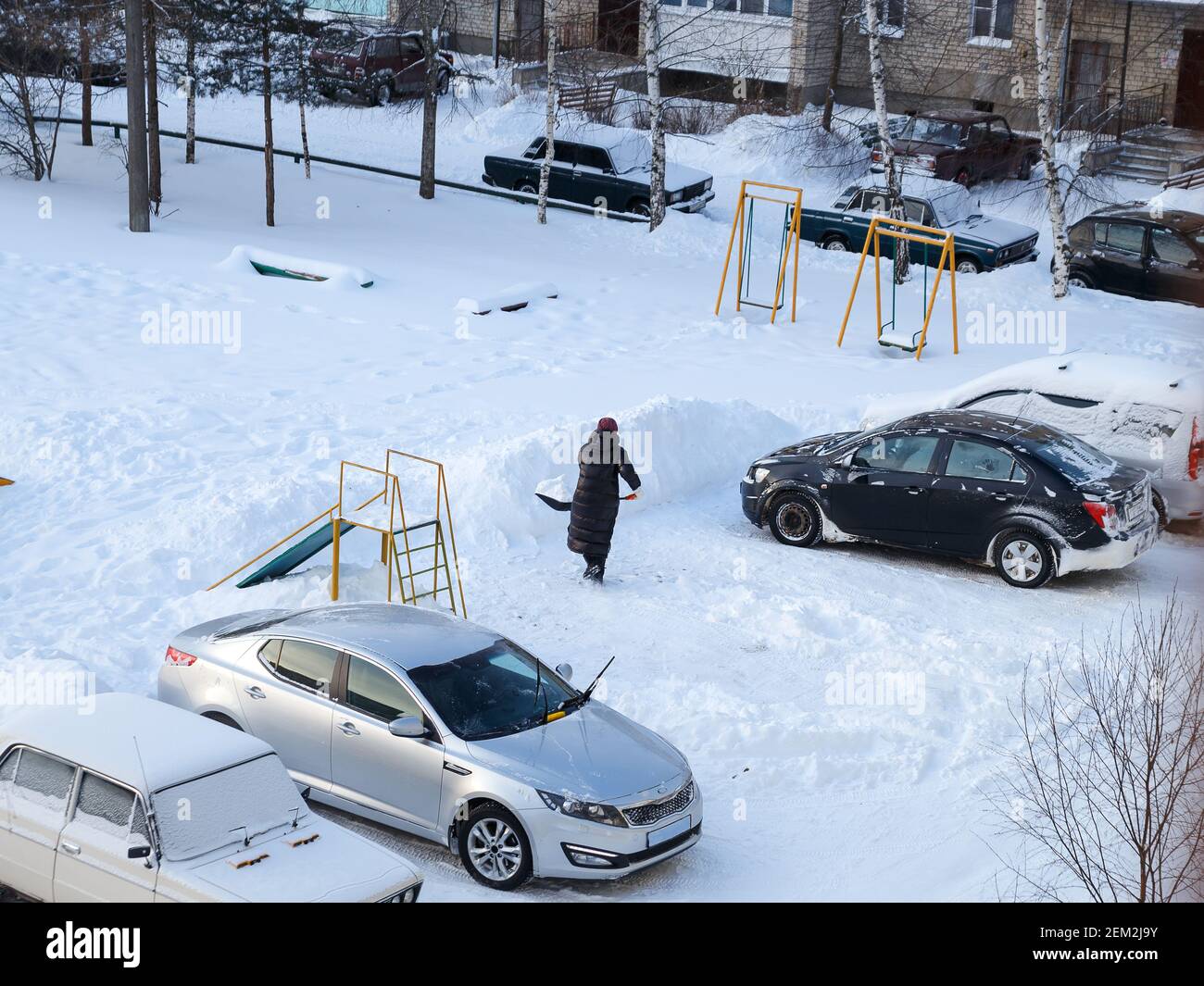 Parking is cleared of snow by woman on winter day Stock Photo - Alamy