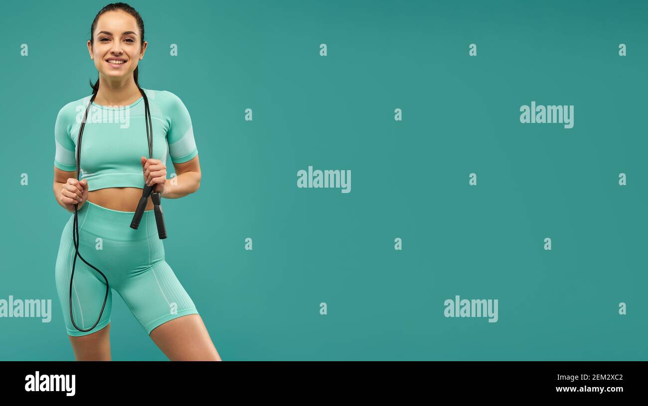 Beautiful fit lady with jump rope around her neck looking at camera and ...
