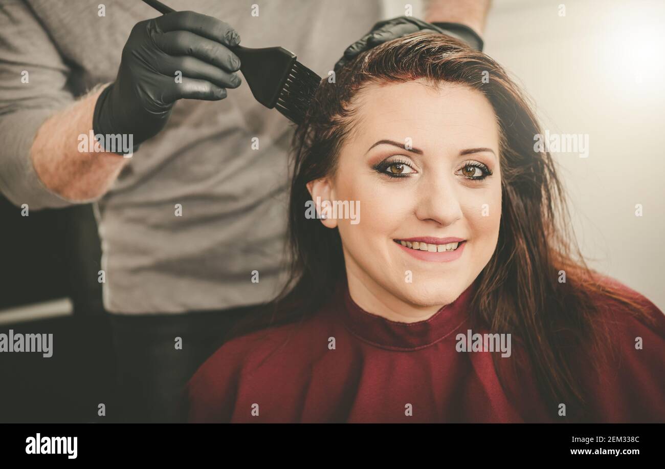 Hairdresser coloring female client hair Stock Photo - Alamy