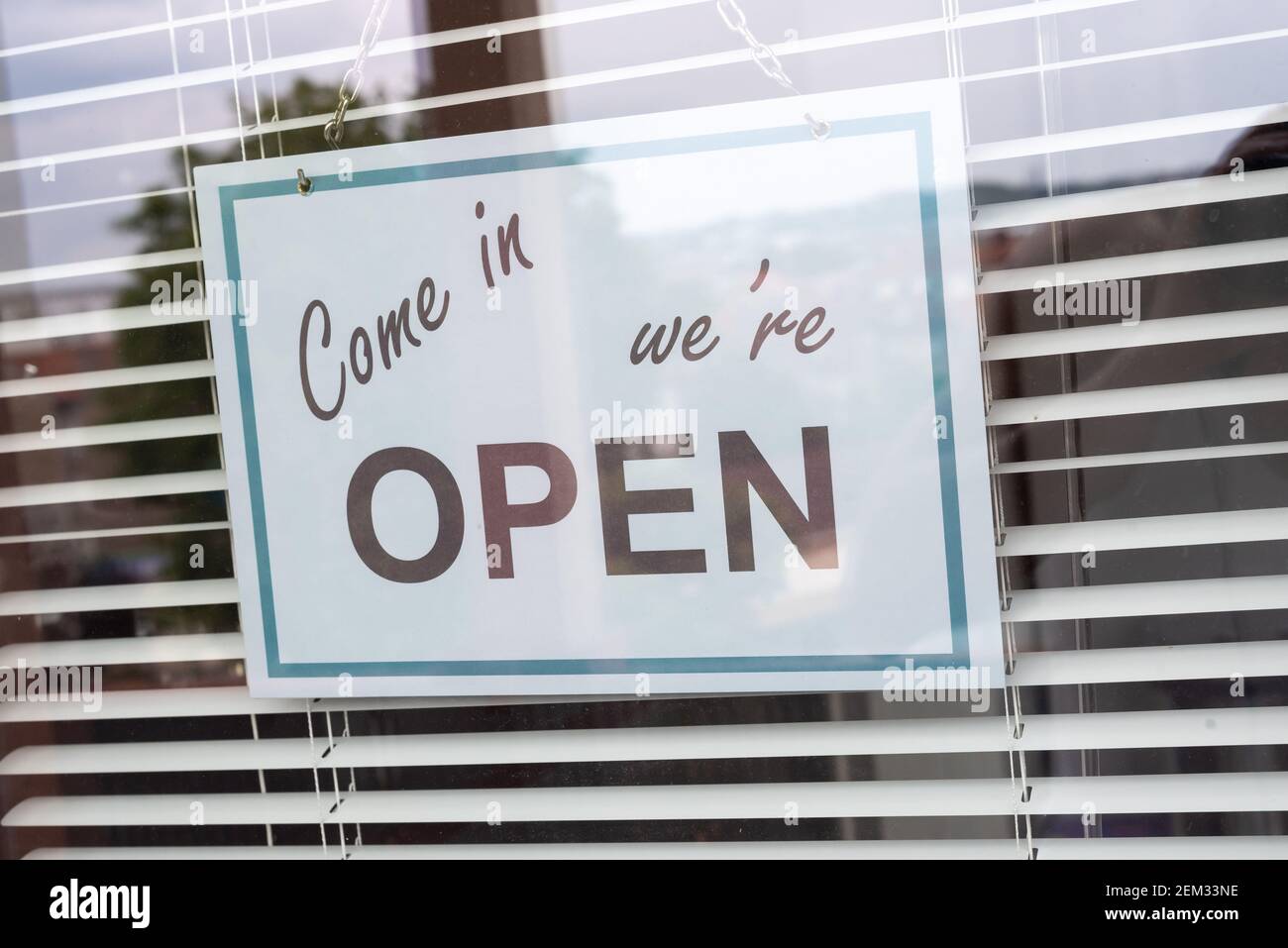 Come in we're open sign hanging behind a store window Stock Photo - Alamy