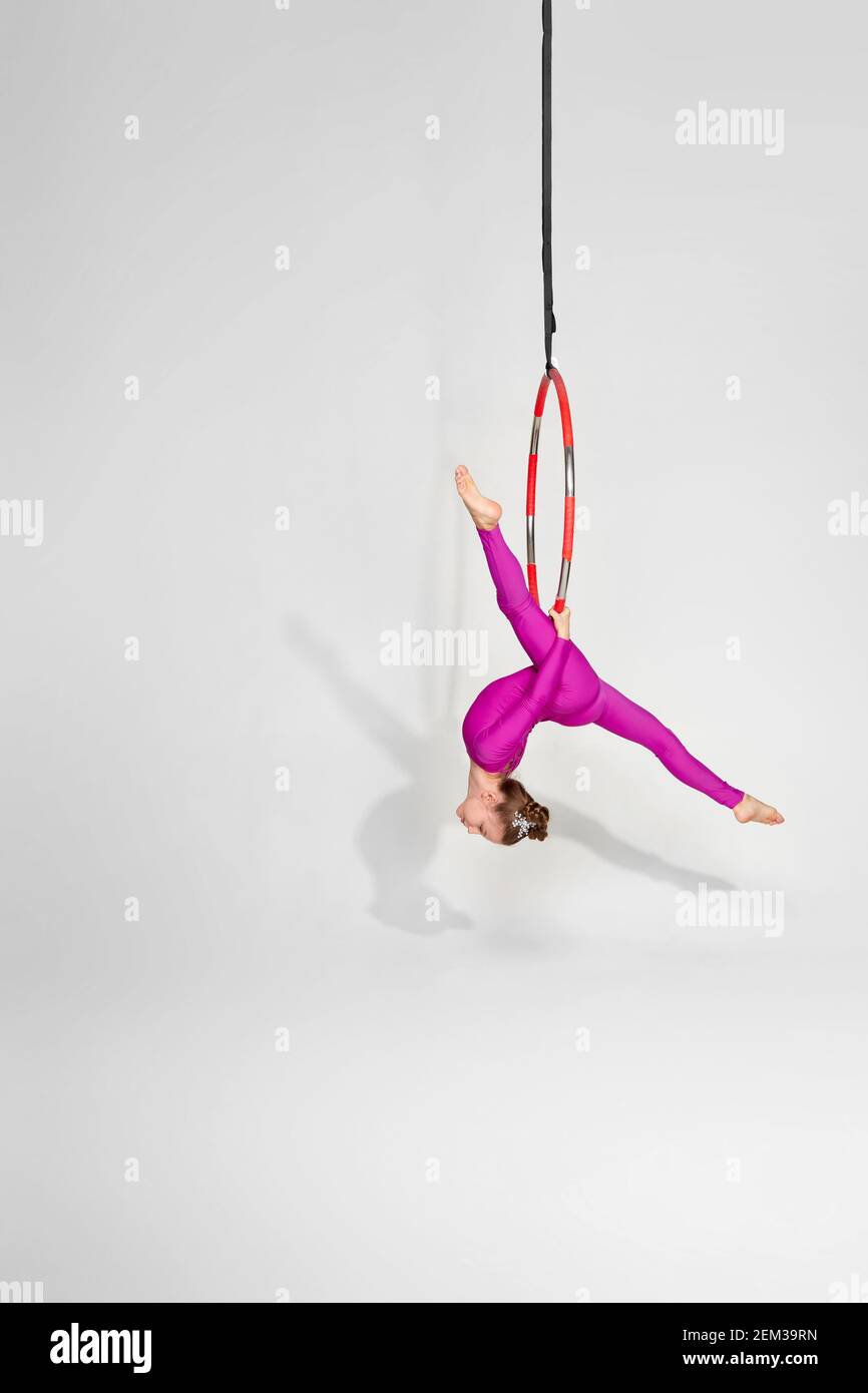 little child girl gymnast in pink sportwear doing twine on an aerial ...