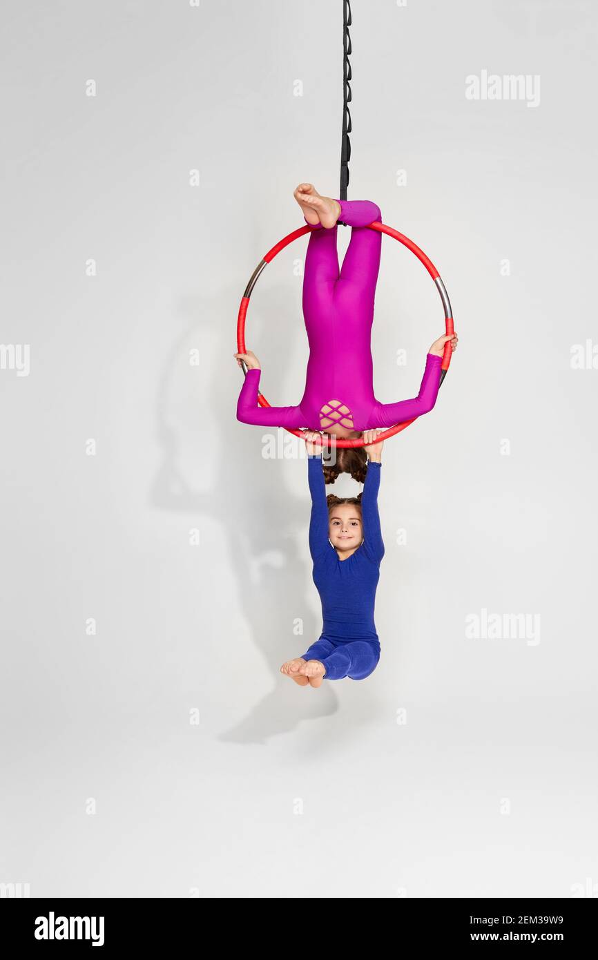 two little child girls shows an acrobatic performance on an aerial hoop ...