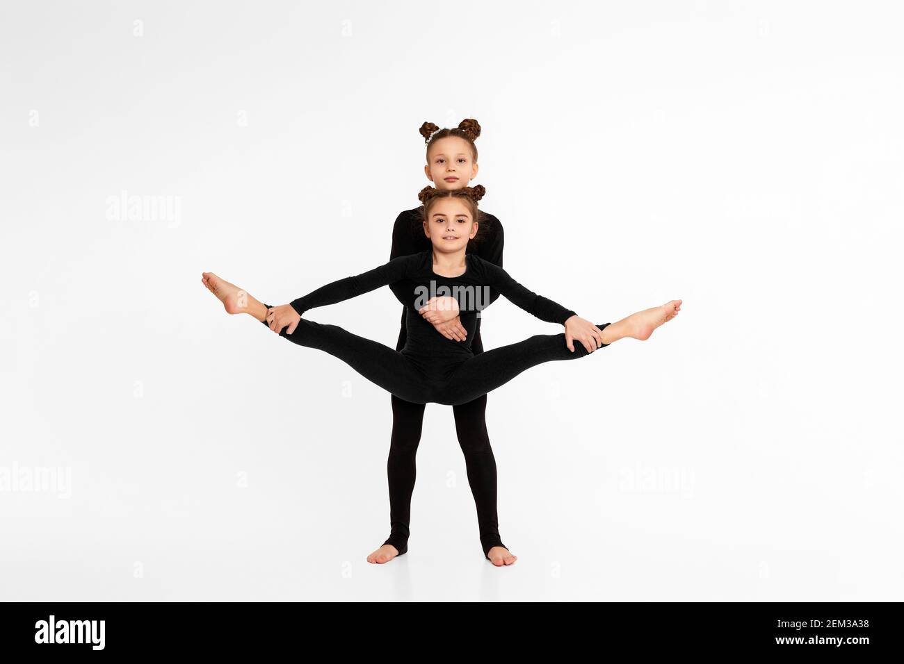 two gymnast child girls show athletic skills on white studio background ...