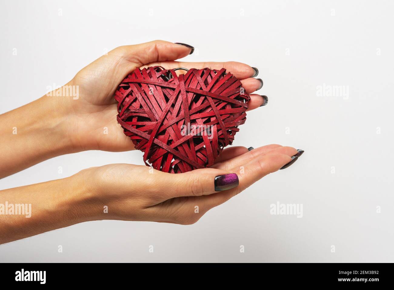 Wicker red heart made of straw in woman's hands on white background ...