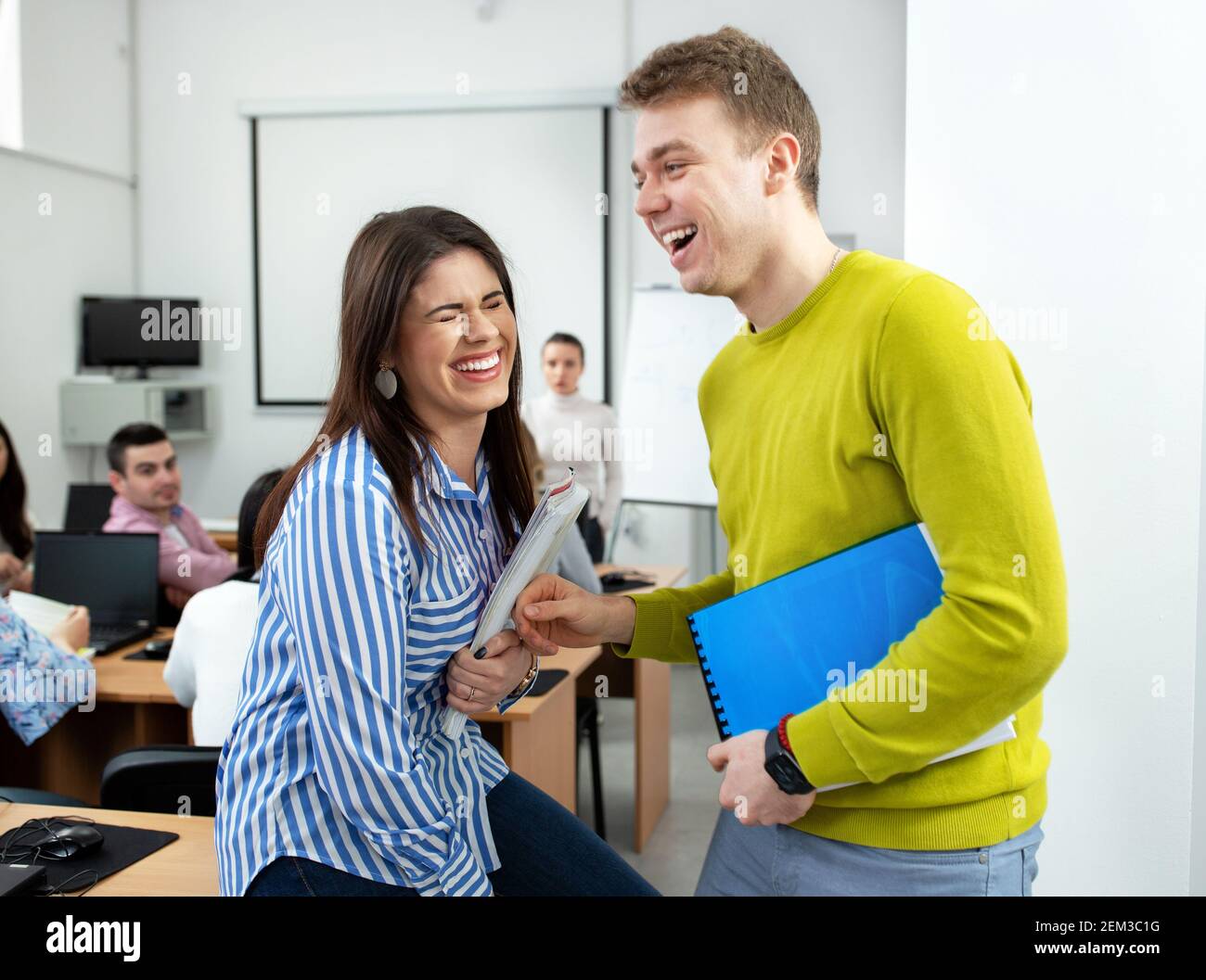 Two young people smiling and flirting in the classroom during a break ...