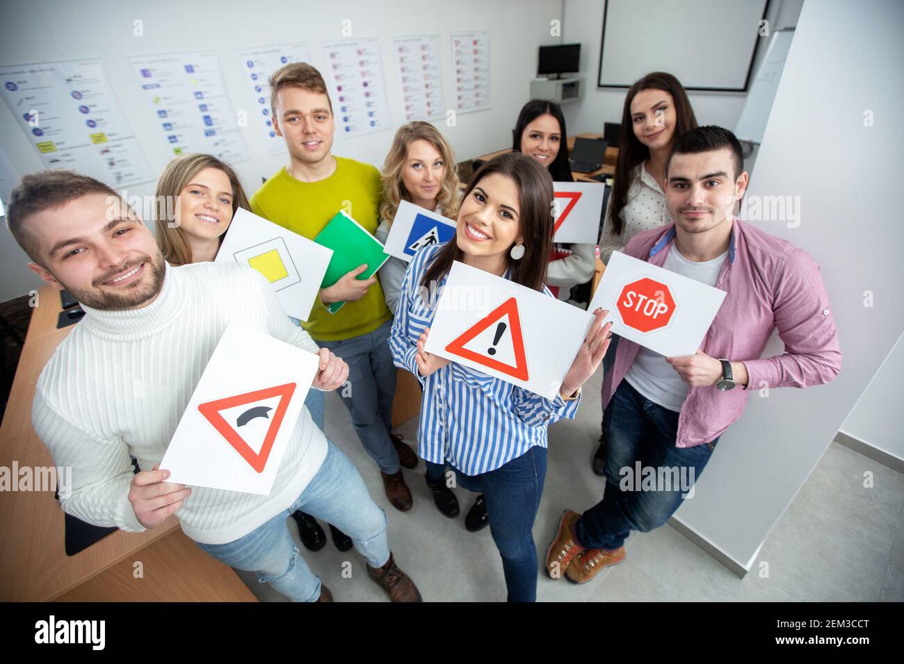 Students holding paper images of road traffic signs in the classroom ...