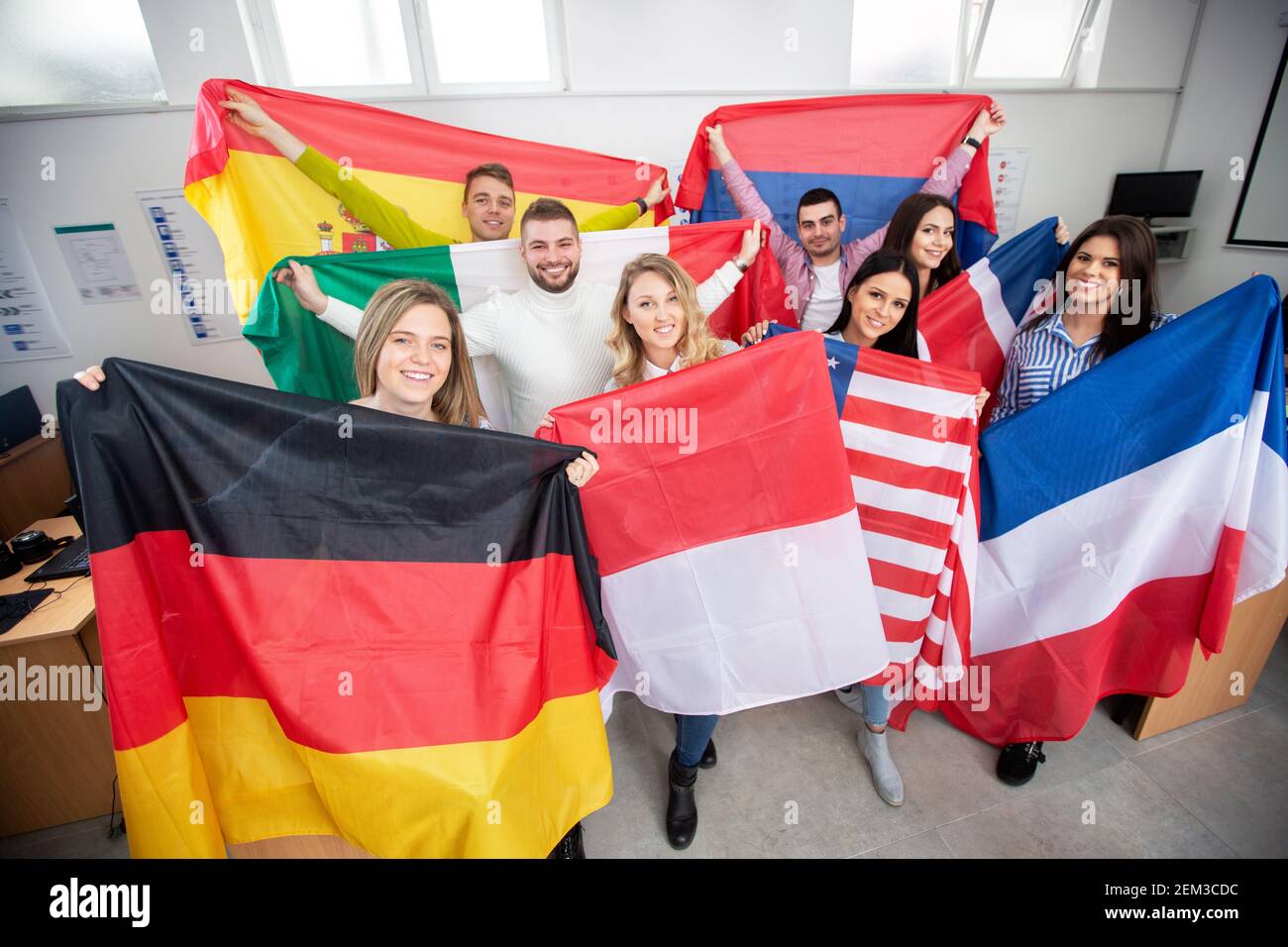 Students holding various flags of different countries in the classroom ...