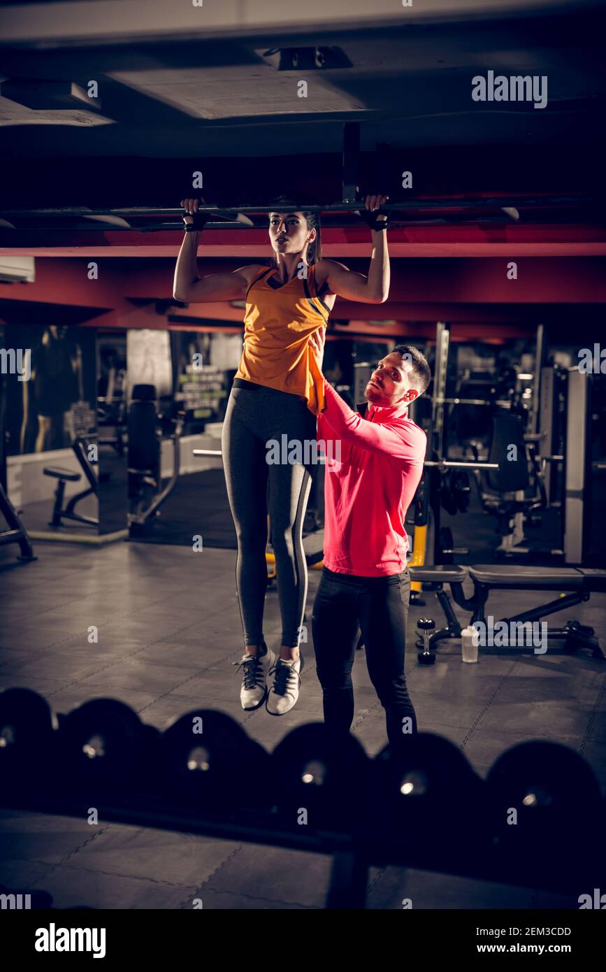 Focused motivated young slim athletic fitness woman doing pull ups ...