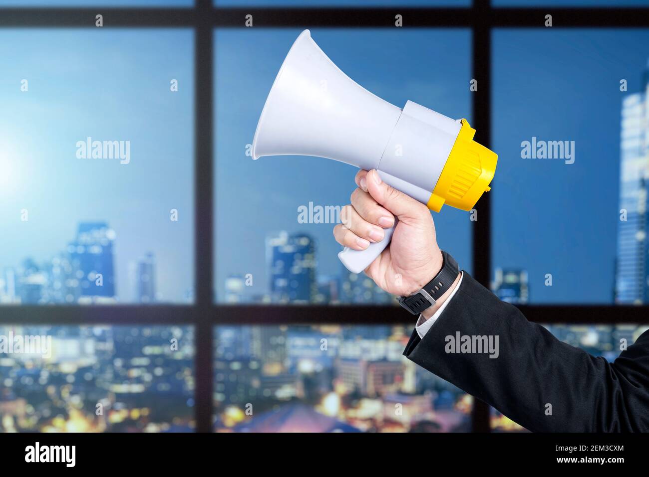 Businessman hand holding megaphone with office building background ...