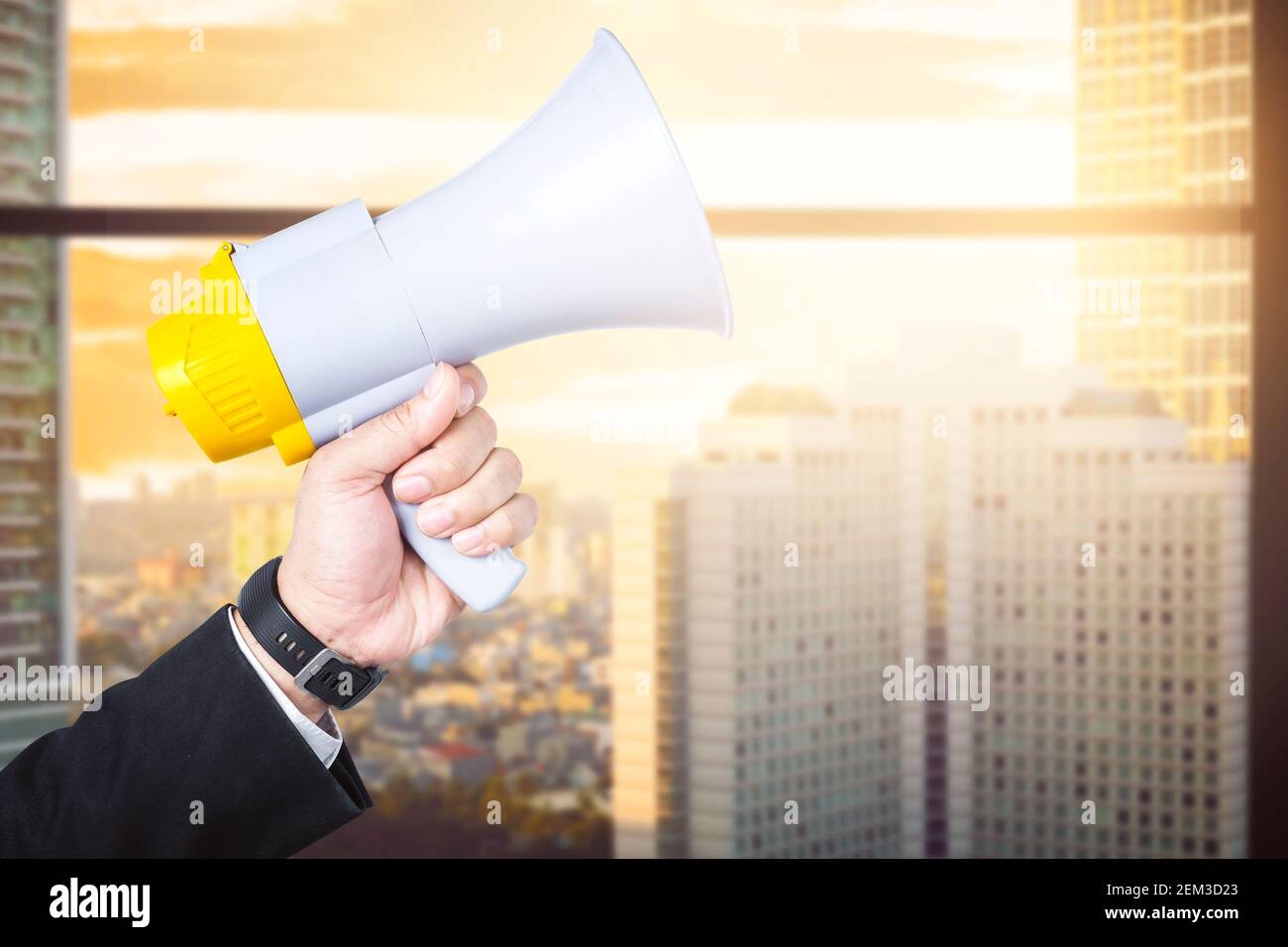 Businessman hand holding megaphone with office building background ...