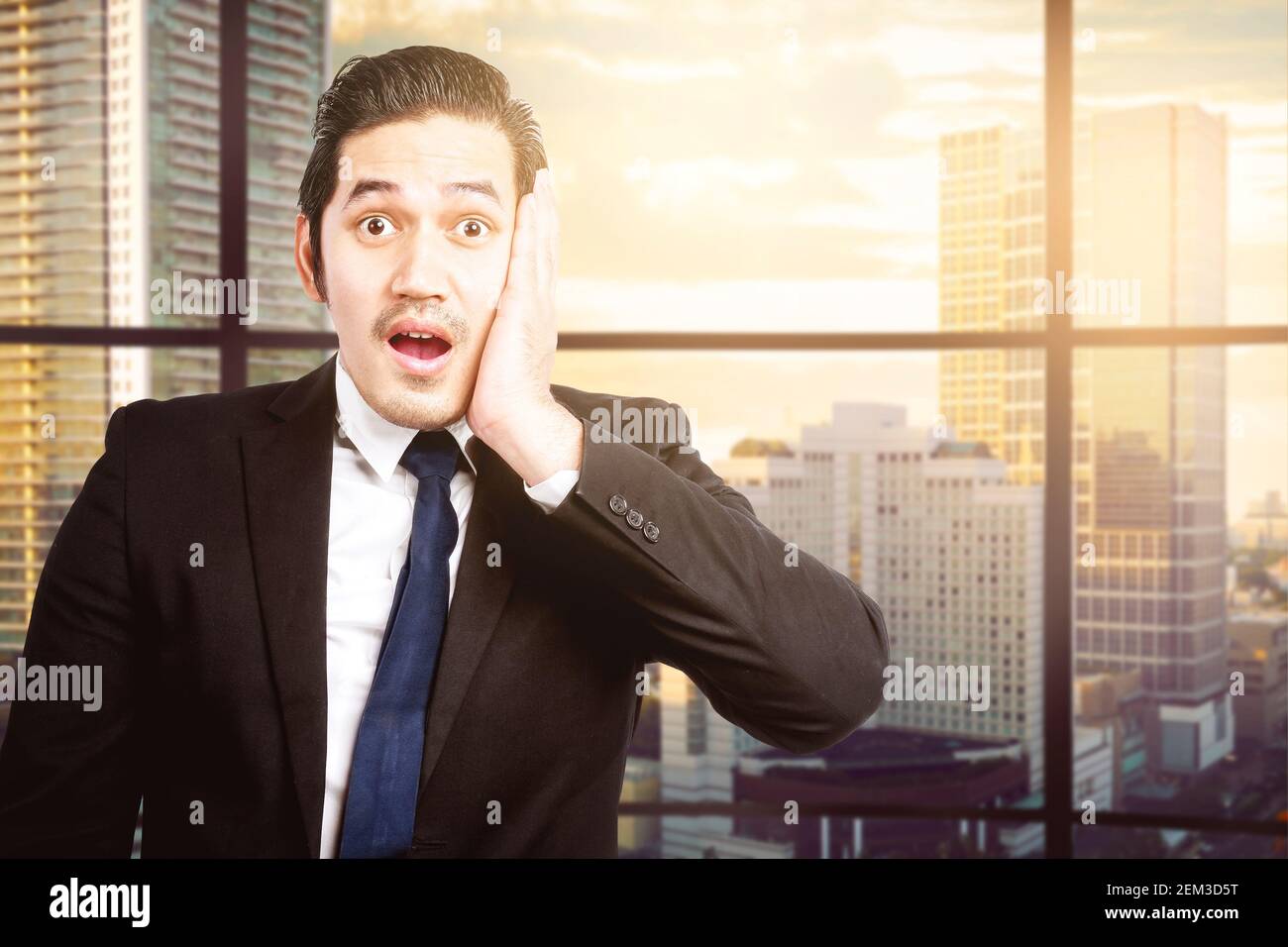 Asian businessman standing with shocked expression on the office ...