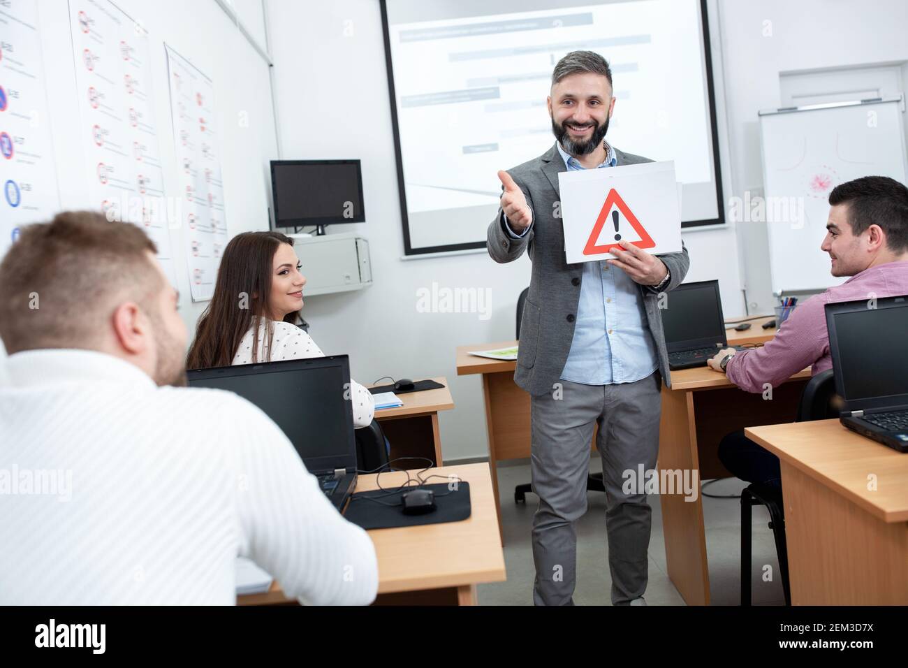 Driving instructor asking students about the traffic sign he is holding ...
