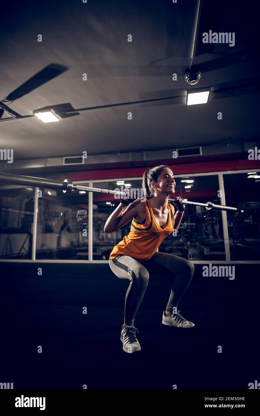 Motivated happy gorgeous young fitness woman crouch and doing squad ...