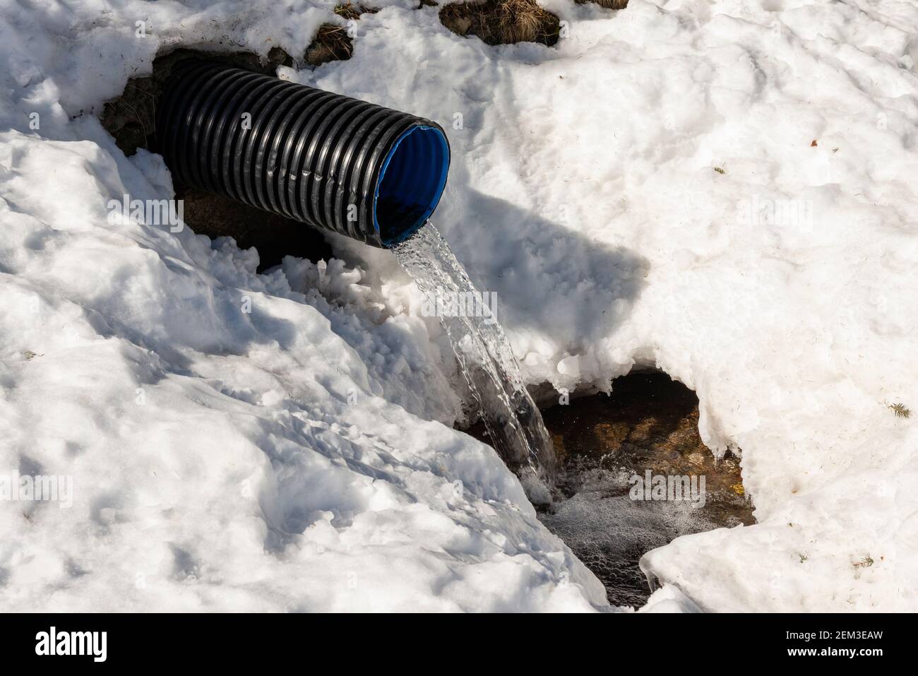Running fresh water flow out of pipe in melting snow as nature ...