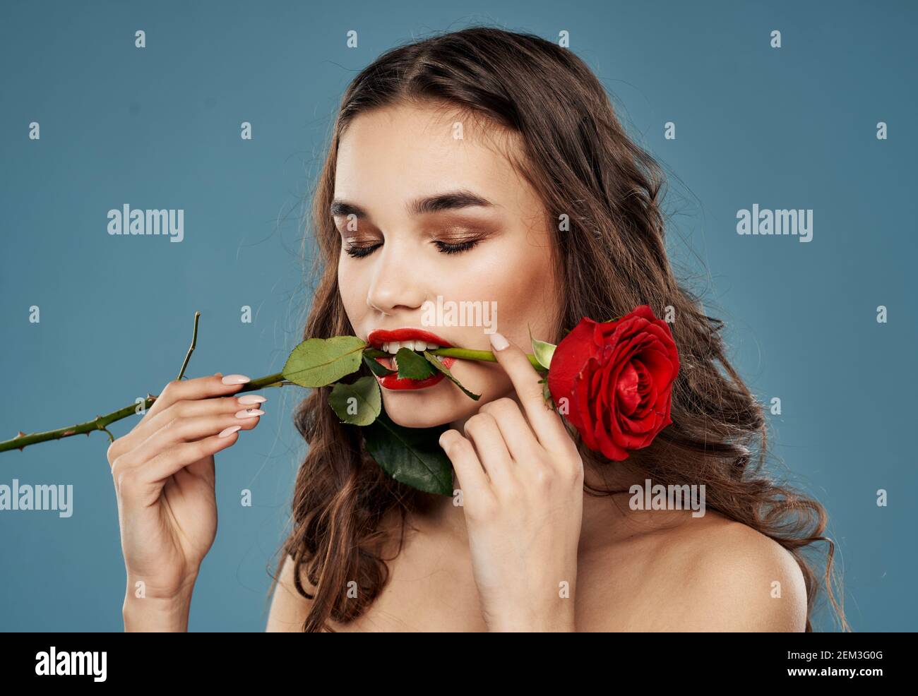 Woman with a rose in her teeth evening makeup blue background model ...