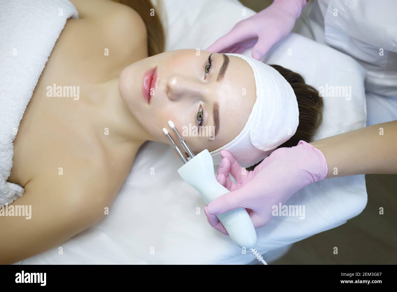 Cosmetologist does microcurrent procedure of a beautiful woman. Women's cosmetology in the ...