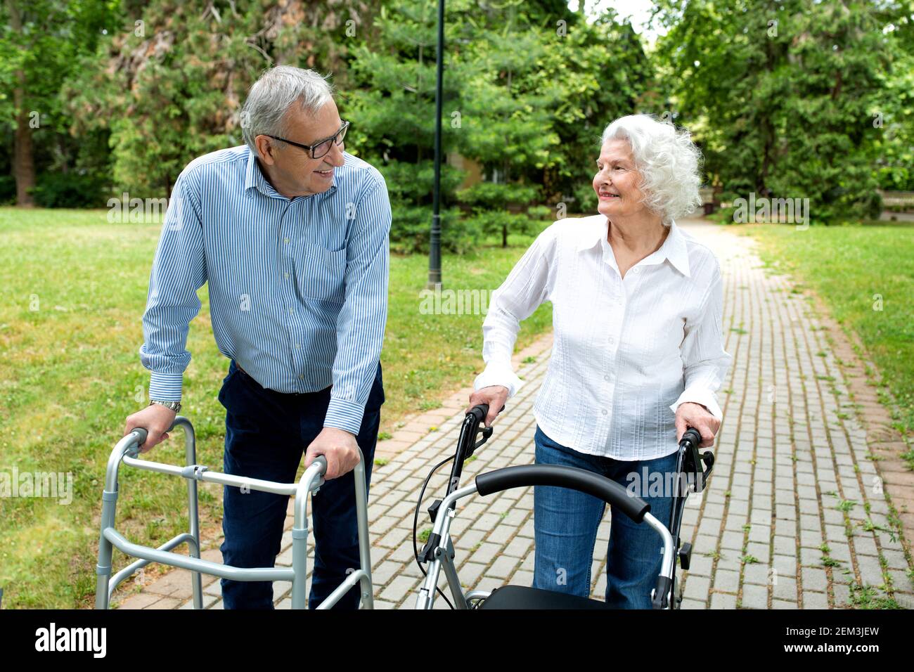 Elder man and a elder woman strolling using walkers Stock Photo - Alamy