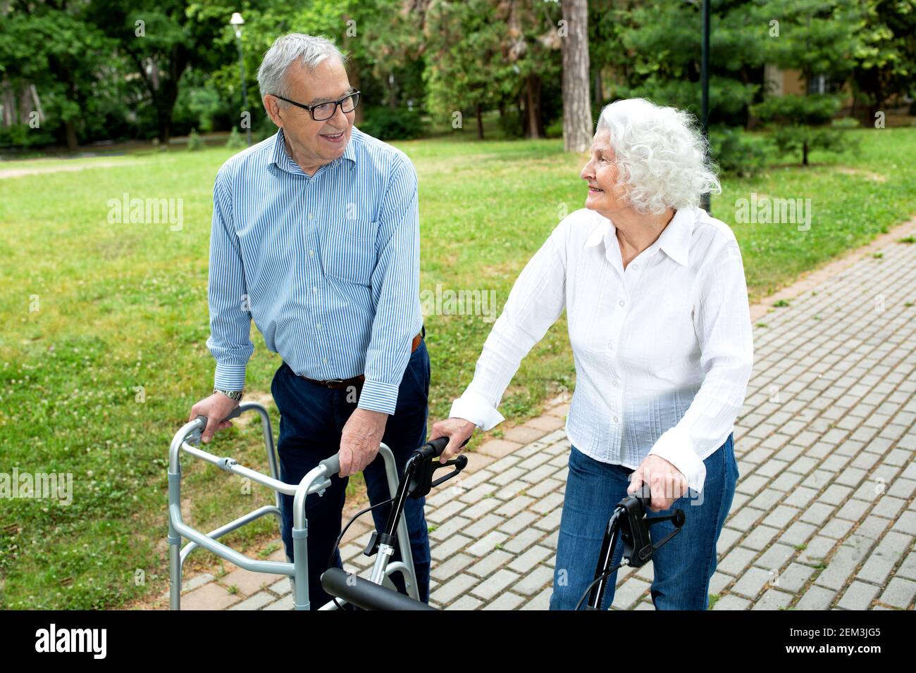 Elderly couple chatting and strolling in the park with a little help of ...
