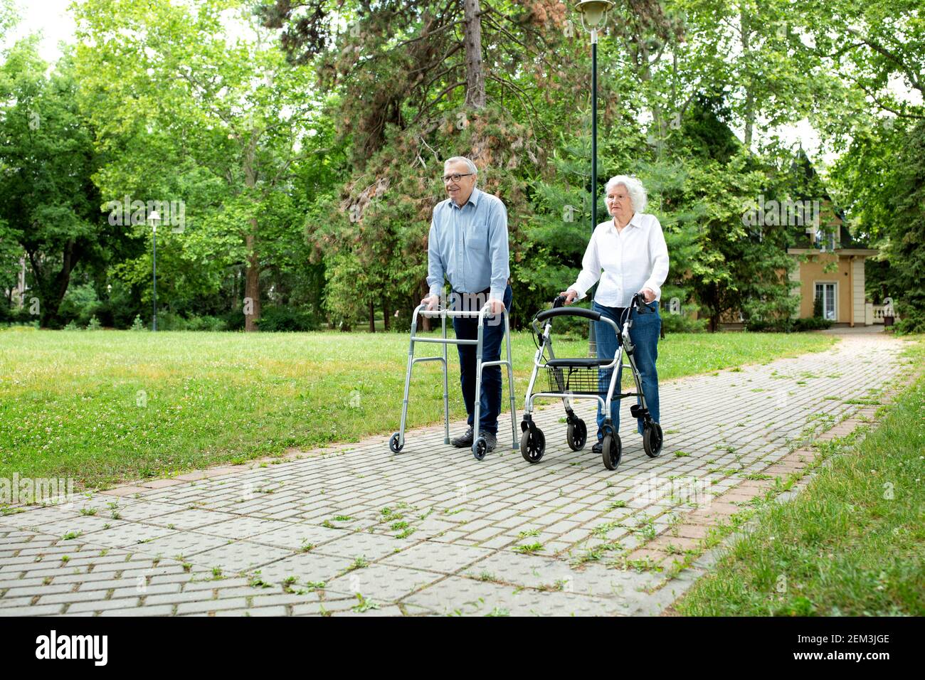 Elderly couple in the park strolling with walkers, senior citizen ...