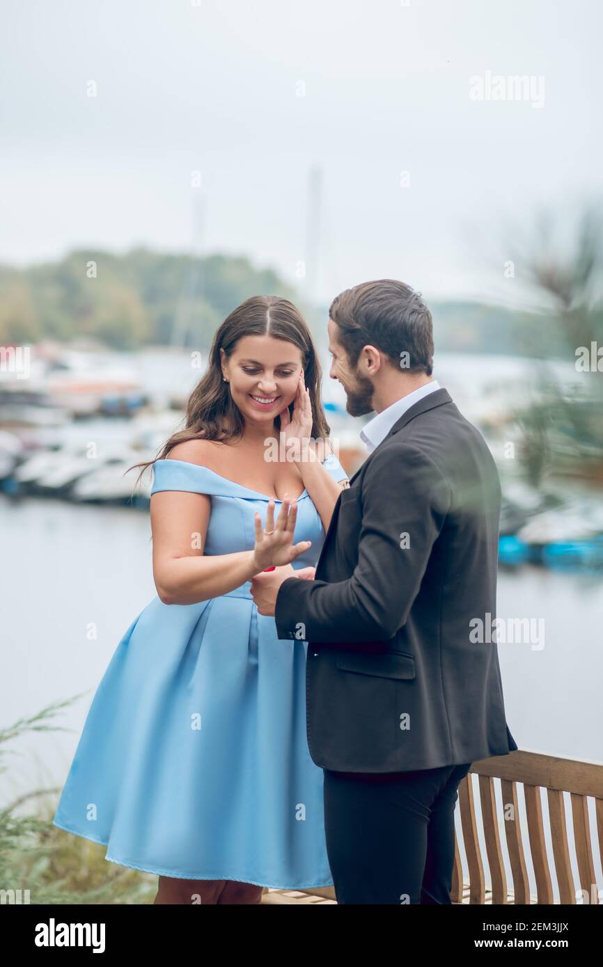Happy woman looking at ring on finger and man Stock Photo - Alamy