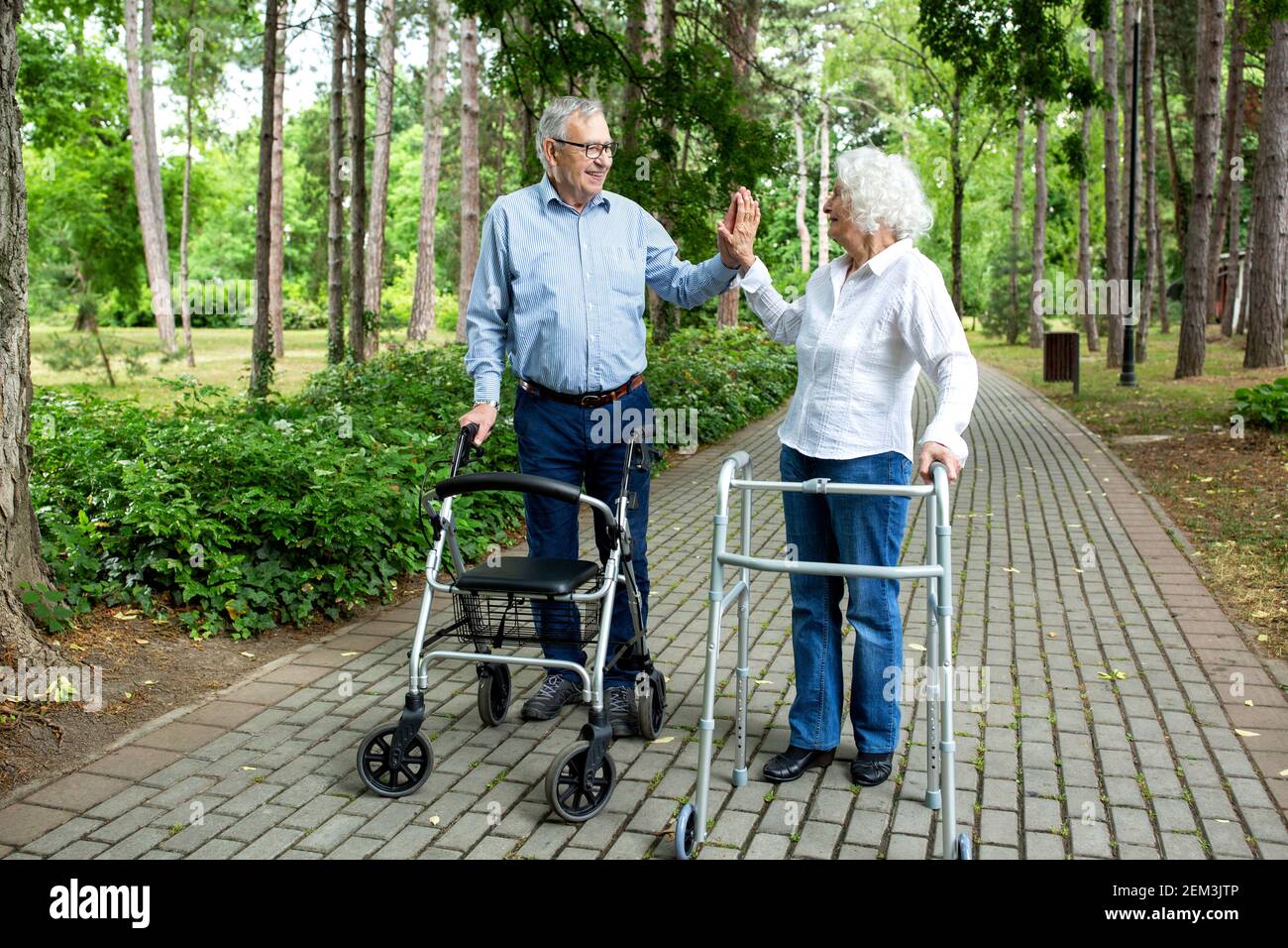 Senior couple in high five mode during a walk with helpers, taking a ...