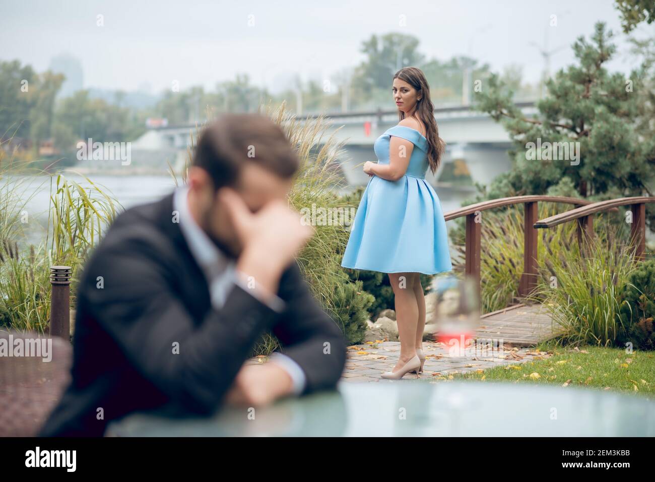 Woman in dress standing at distance and unhappy man Stock Photo - Alamy
