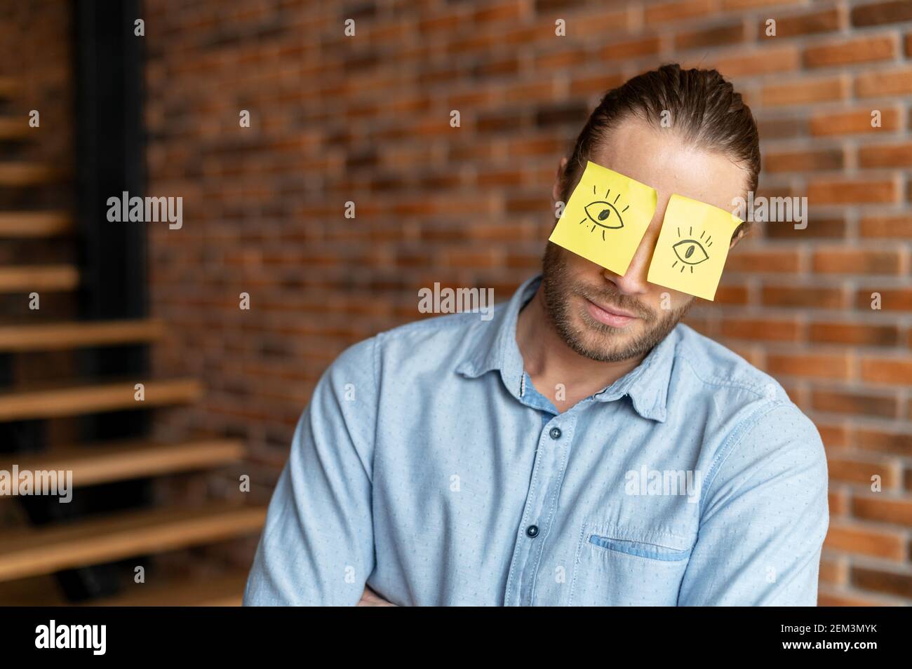 Tired man with yellow stickers with painted eyes on the face , sleeping ...