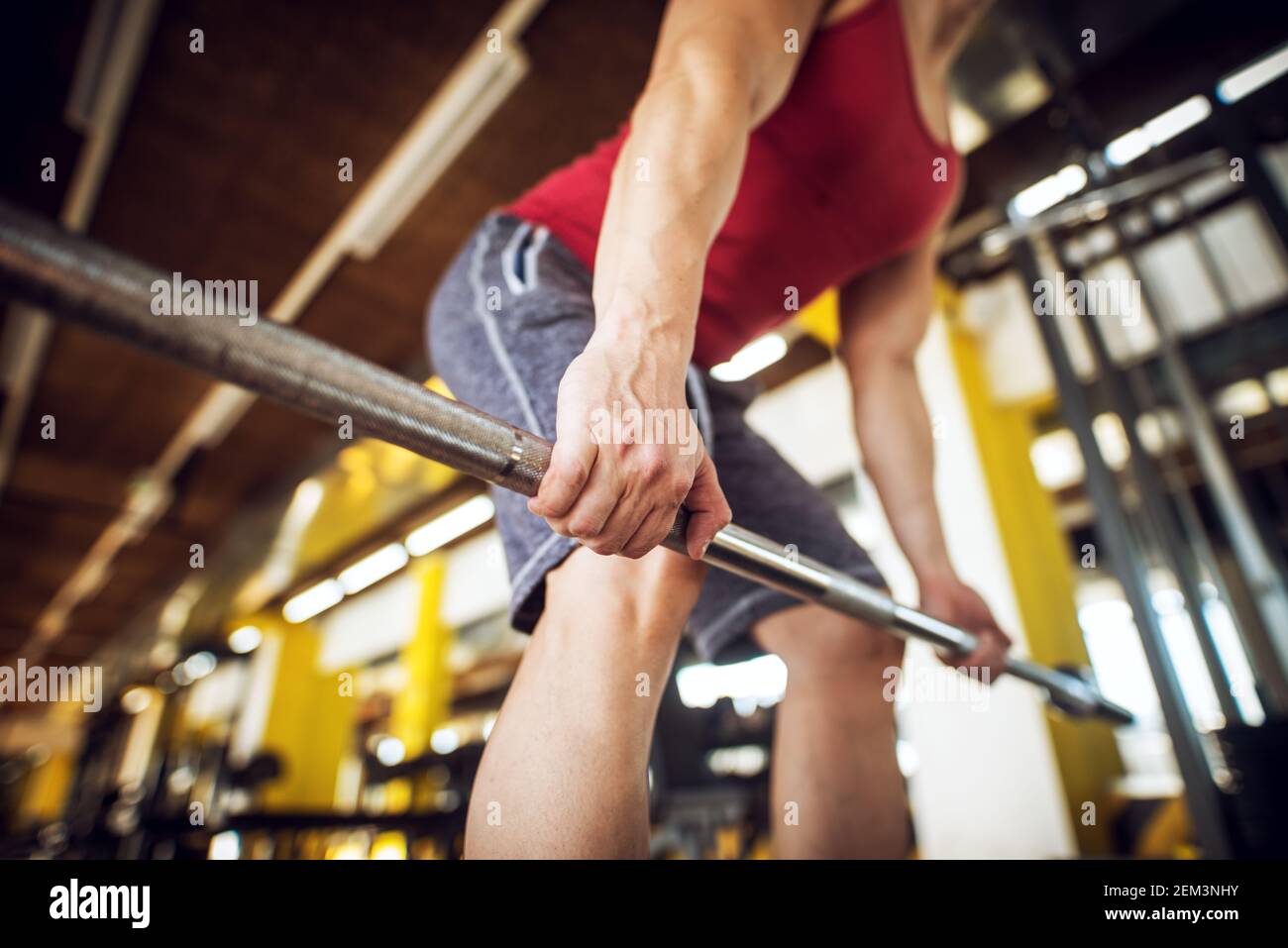 Close up focus view of bar while strong young muscular bodybuilder man ...