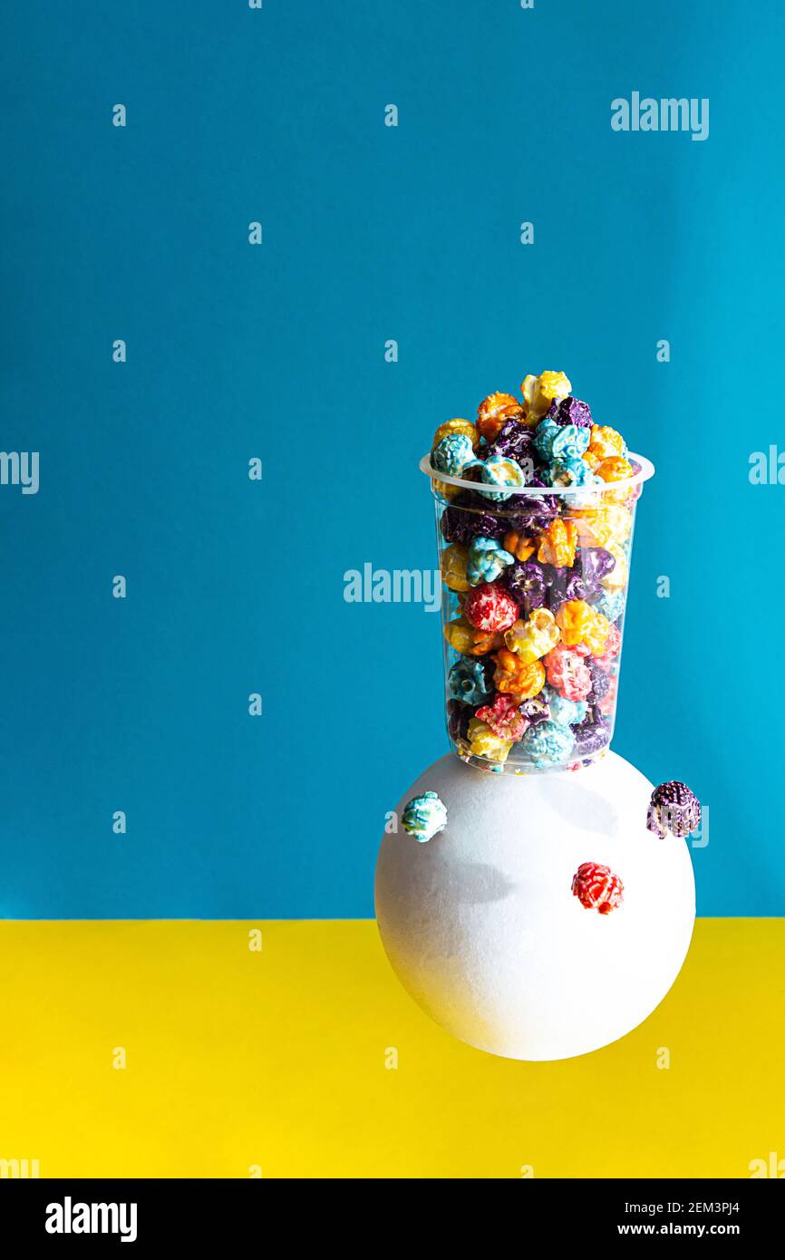 Creative composition with colored popcorn in a transparent glass on a ...