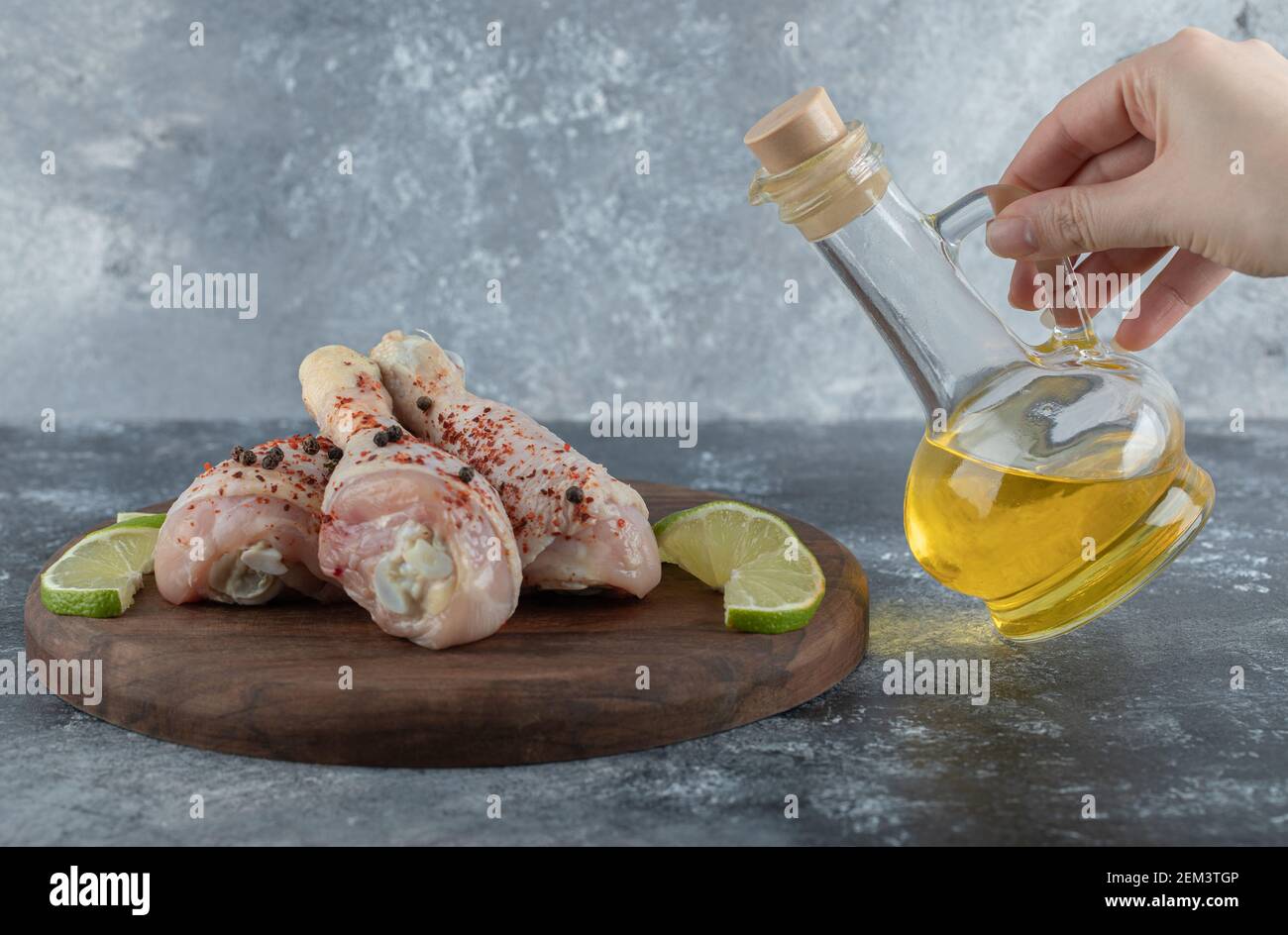Female pouring oil fresh raw chicken legs Stock Photo - Alamy