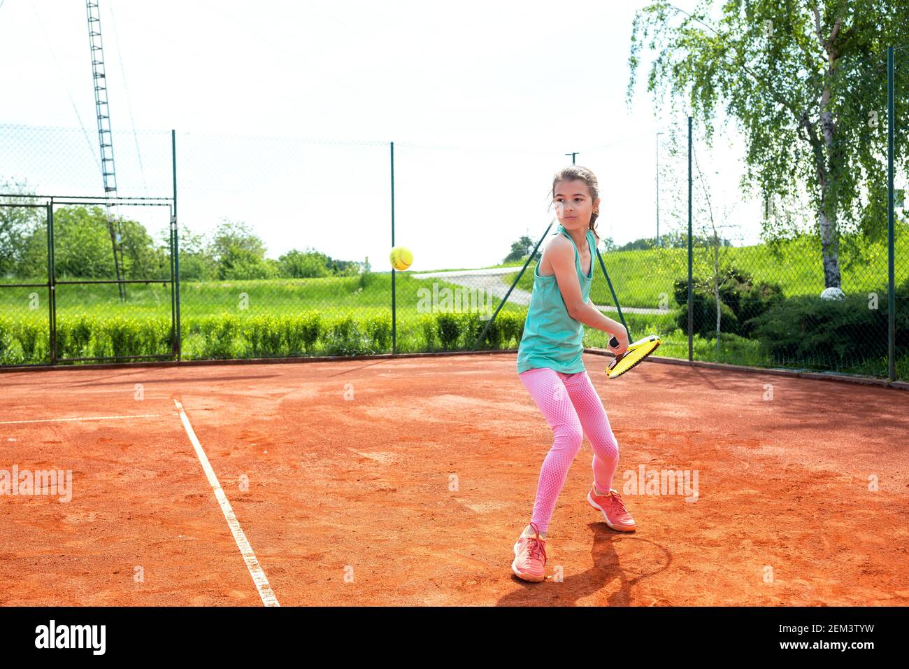 Junior girl practicing a backhand stroke as she plays tennis Stock ...
