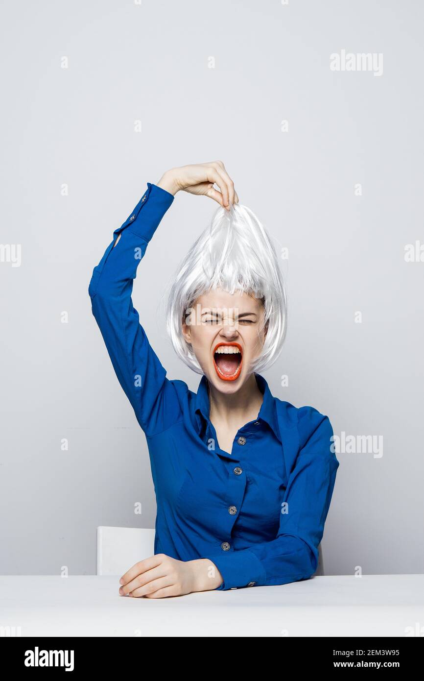 woman takes off white wig from head emotions sit at table cup of drink ...