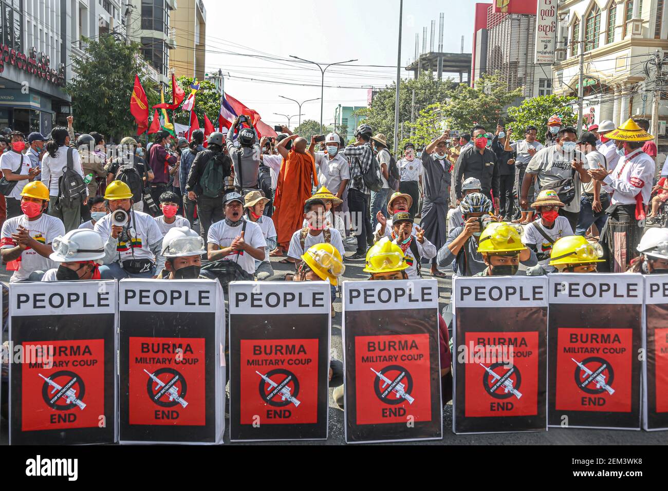Protesters wearing safety helmets create a barricade to shield their ...