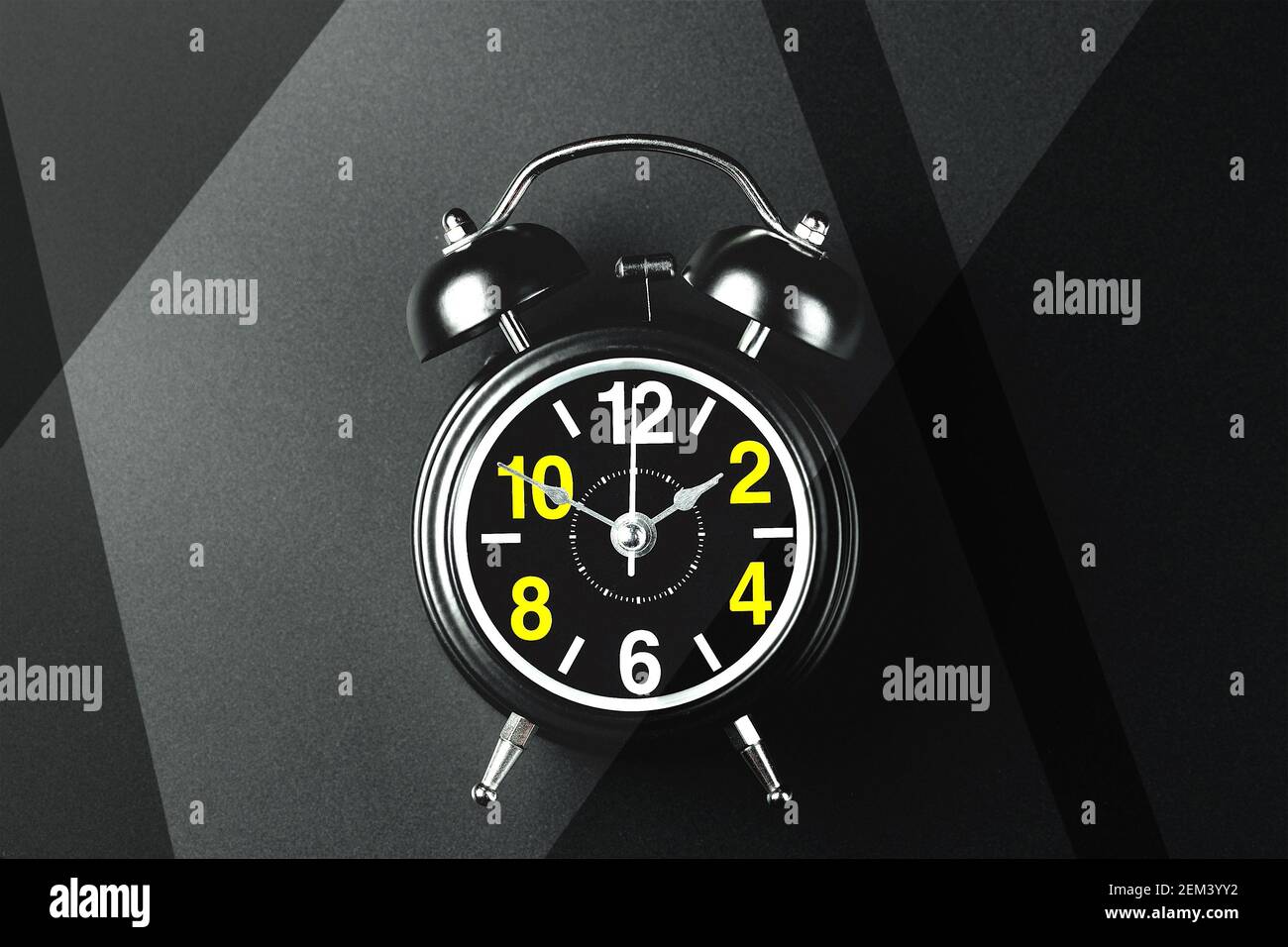 This is a stylish round alarm clock on metal legs on a dark background ...