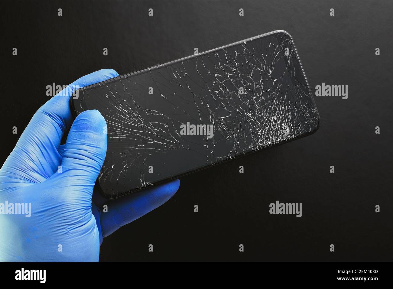 A broken touch phone with a cracked screen in your hand on a black ...