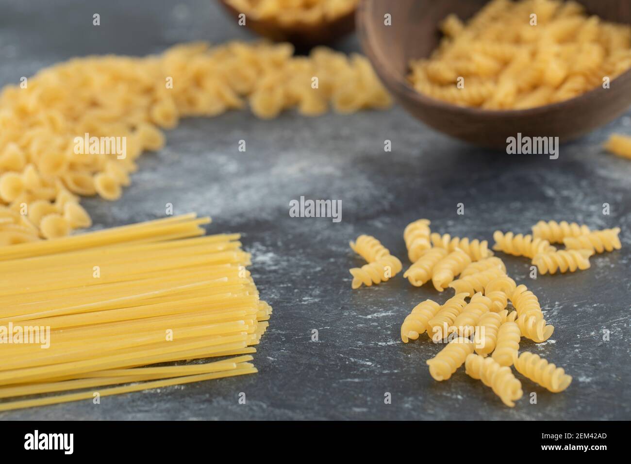 Various types of uncooked pasta with wooden spoons Stock Photo - Alamy
