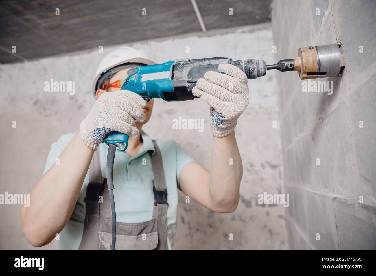 Builder man cutting electrical chase in concrete wall with hammer drill ...