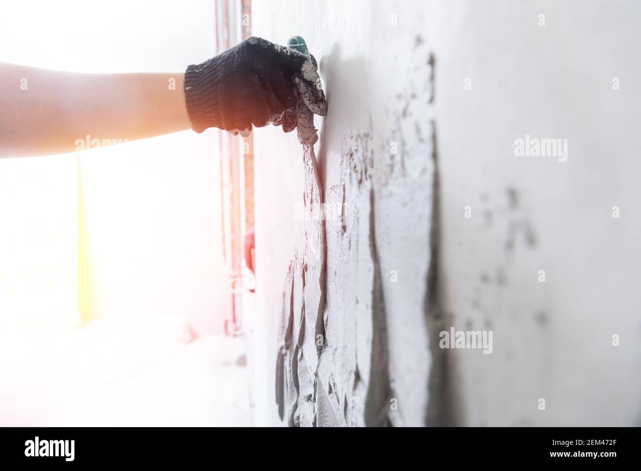 Initial application of putty and plaster on concrete wall to level ...