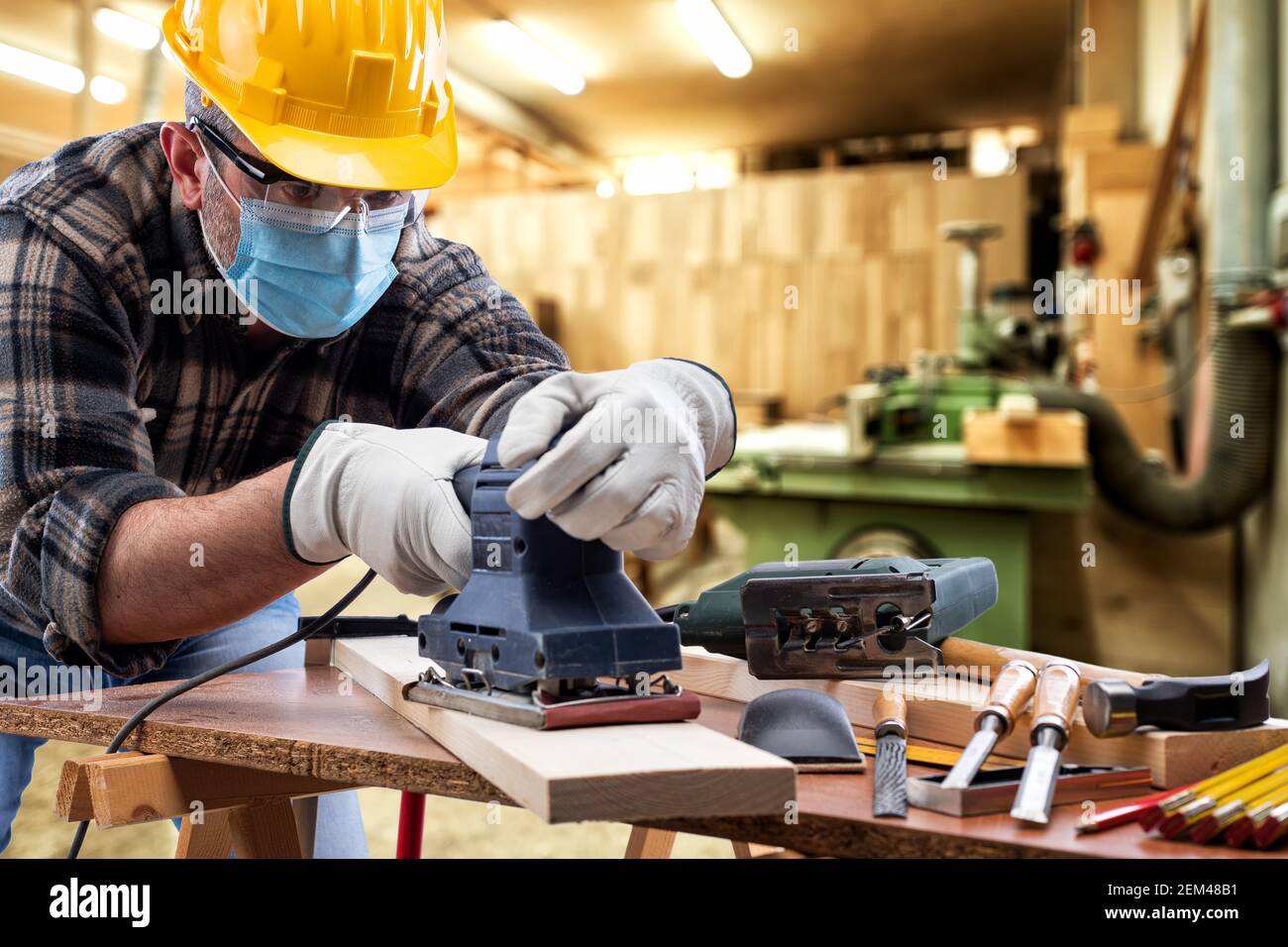 Carpenter worker at work in the carpentry workshop, wears helmet ...