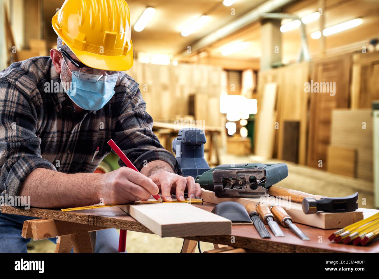 Carpenter worker at work in the carpentry workshop, wears helmet ...